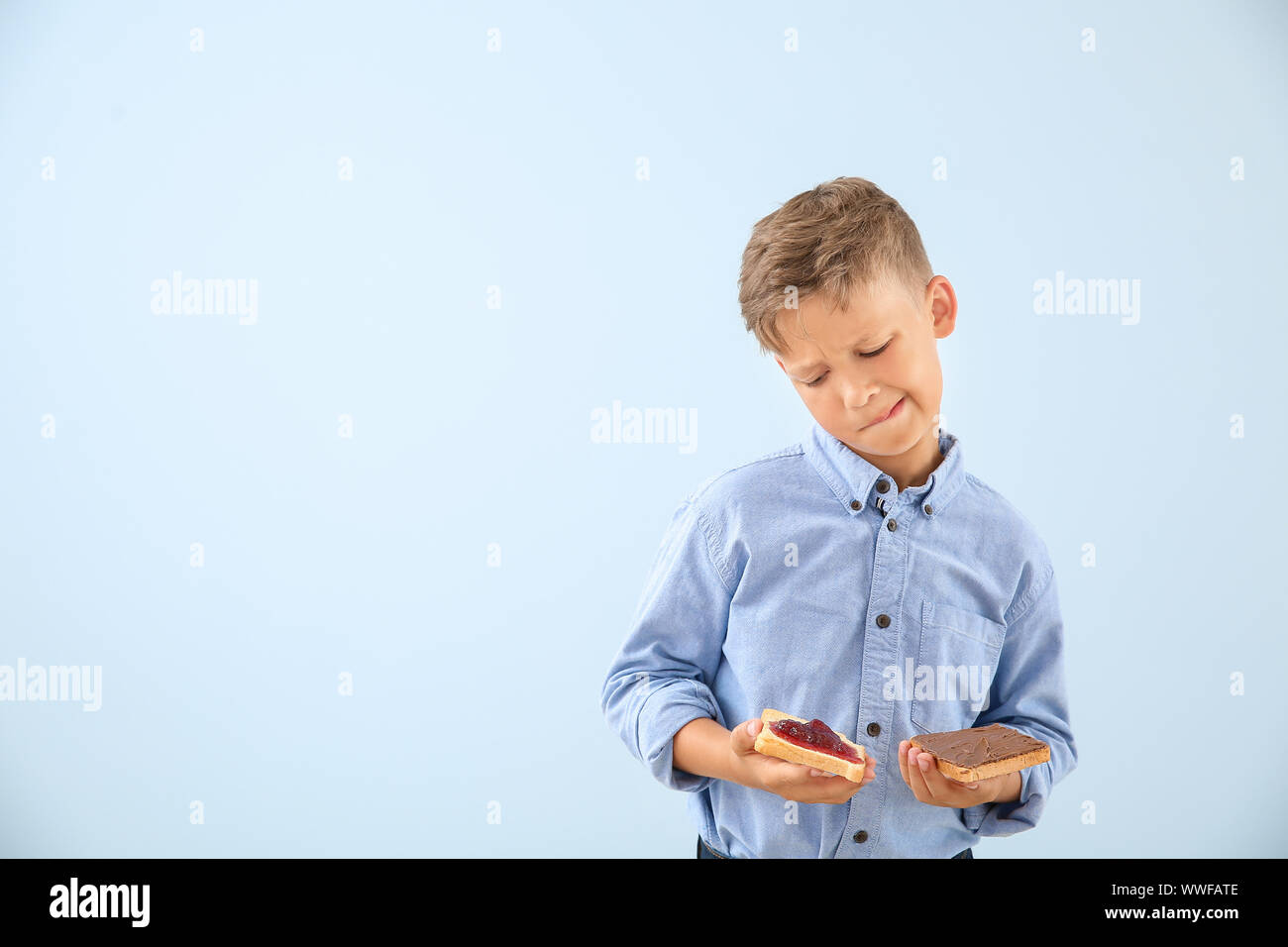 Funny little boy choosing between toast with jam and toast with ...