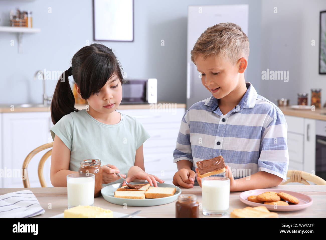Funny little children eating tasty toasts in kitchen Stock Photo - Alamy