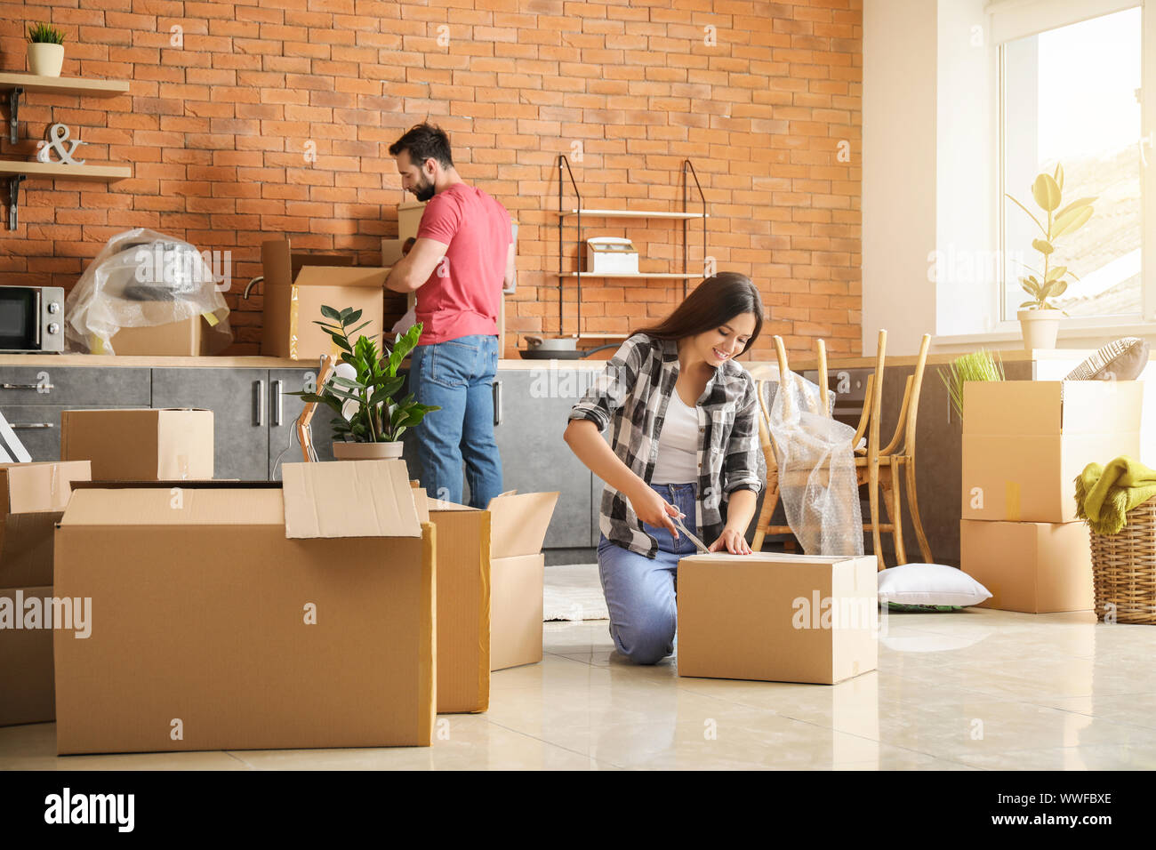 Young couple unpacking things after moving into new house Stock Photo ...