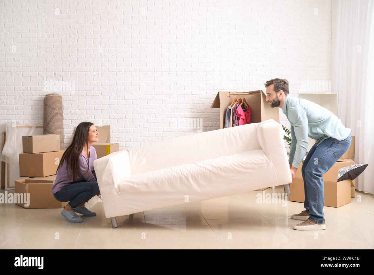 Young couple carrying sofa after moving into new house Stock Photo - Alamy