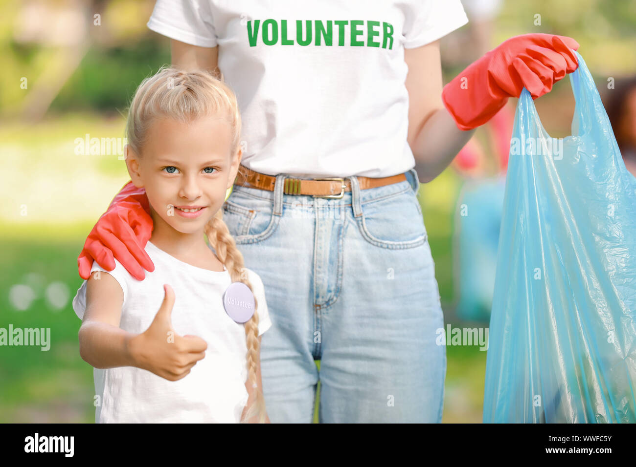 Little volunteer with woman gathering garbage in park Stock Photo - Alamy