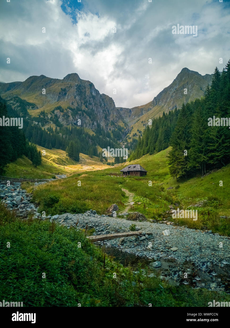 Wooden house at the base of the mountain with river flowing nearby ...