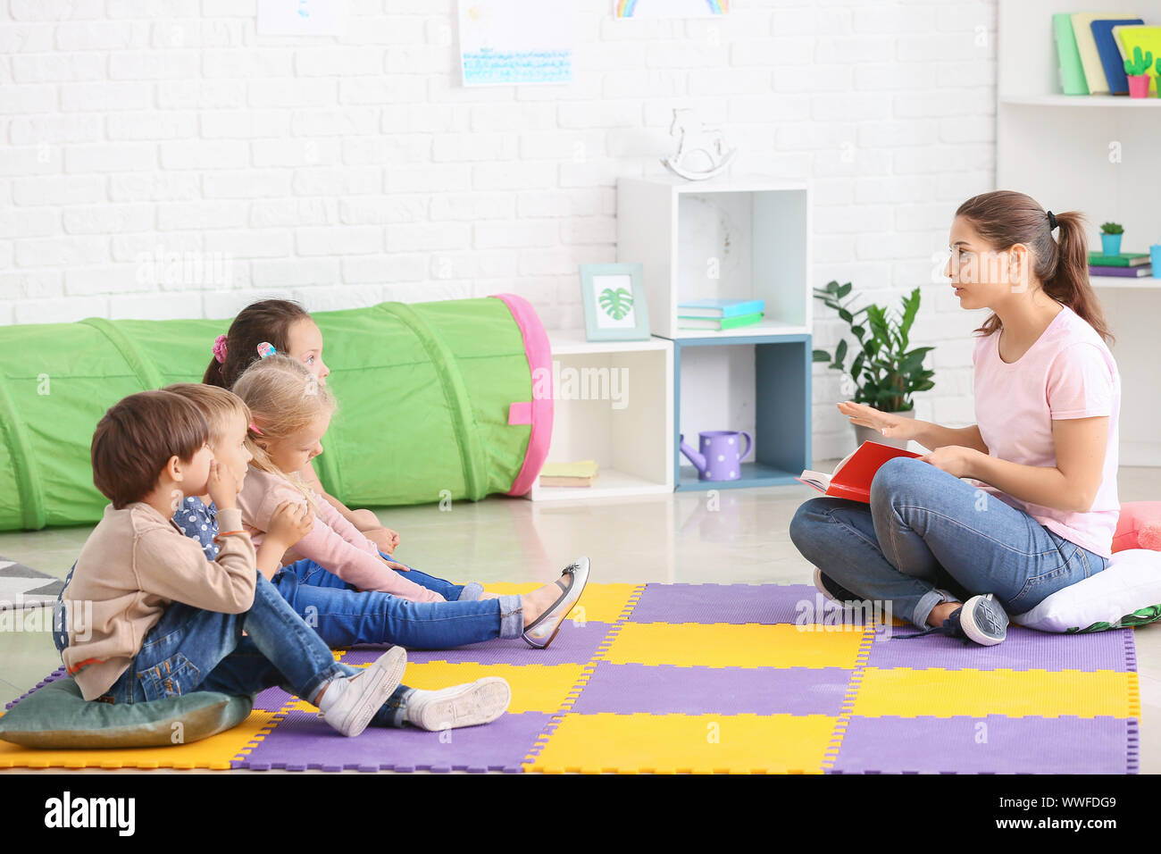 Nursery teacher with cute little children in kindergarten Stock Photo ...