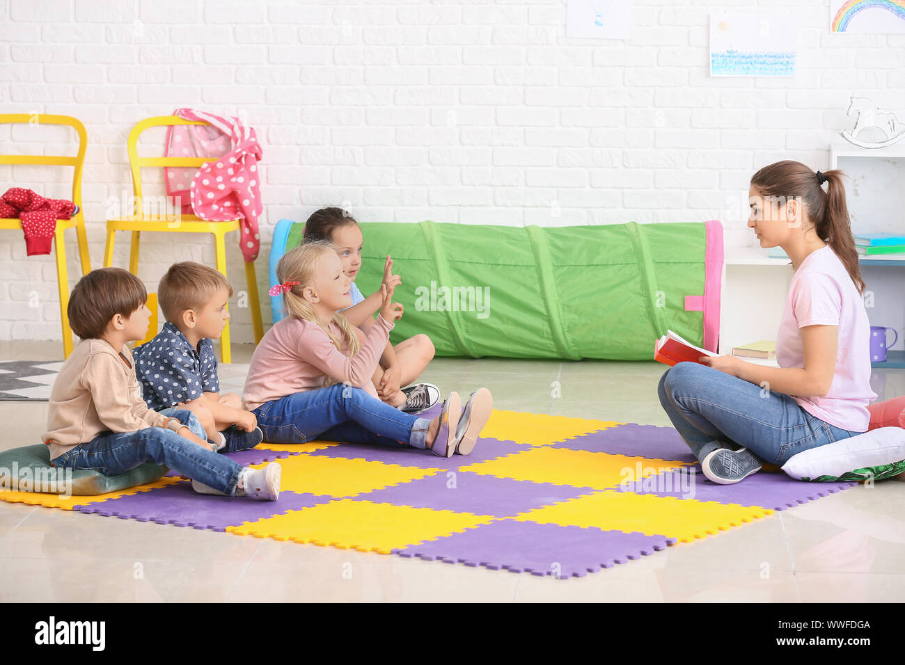 Nursery teacher with cute little children in kindergarten Stock Photo ...
