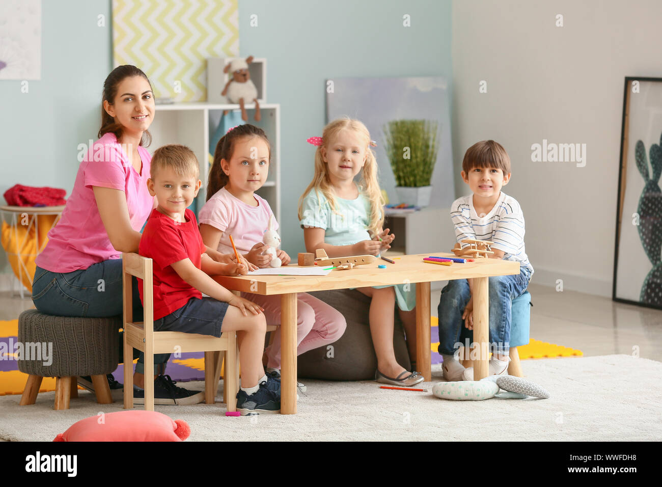 Nursery teacher with cute little children in kindergarten Stock Photo ...