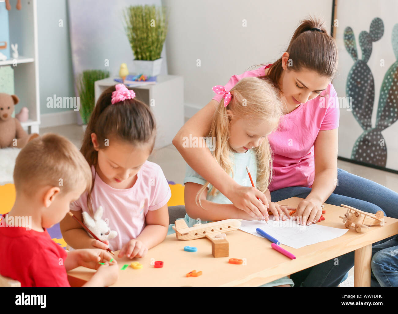 Nursery teacher with cute little children in kindergarten Stock Photo ...