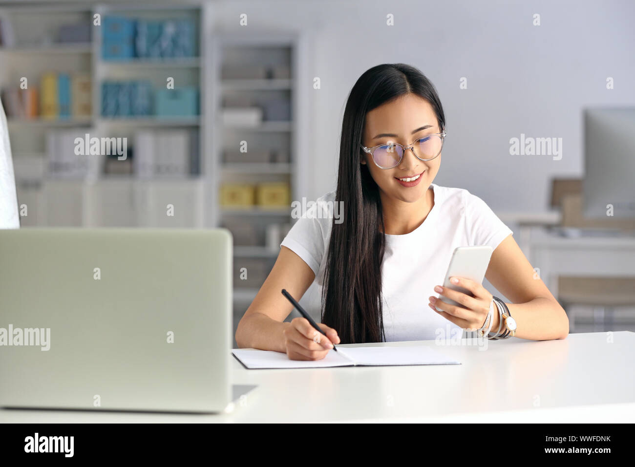 Young Asian student using mobile phone while preparing for exam Stock ...