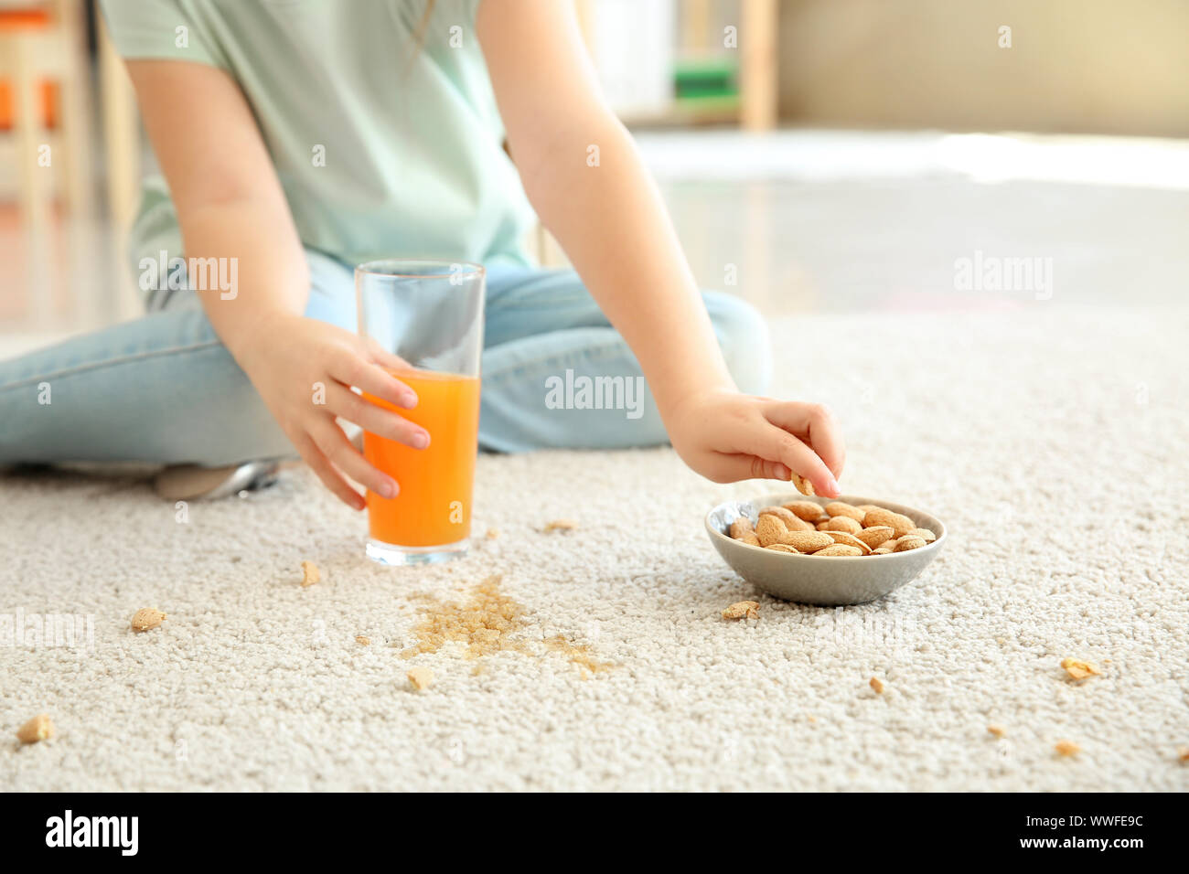 Careless little girl eating nuts and drinking juice while sitting on ...