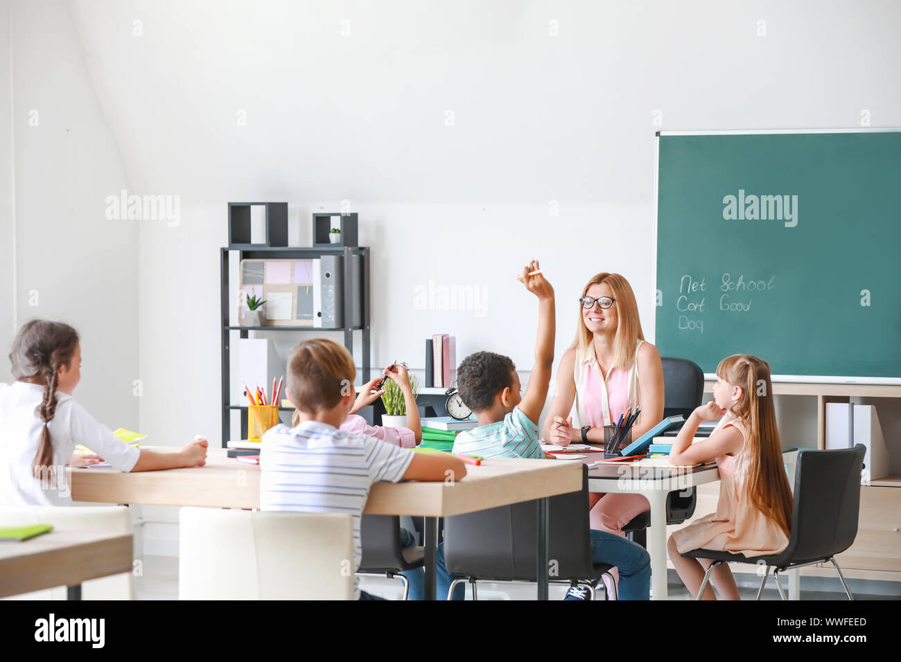 Cute children with teacher during lesson in classroom Stock Photo - Alamy