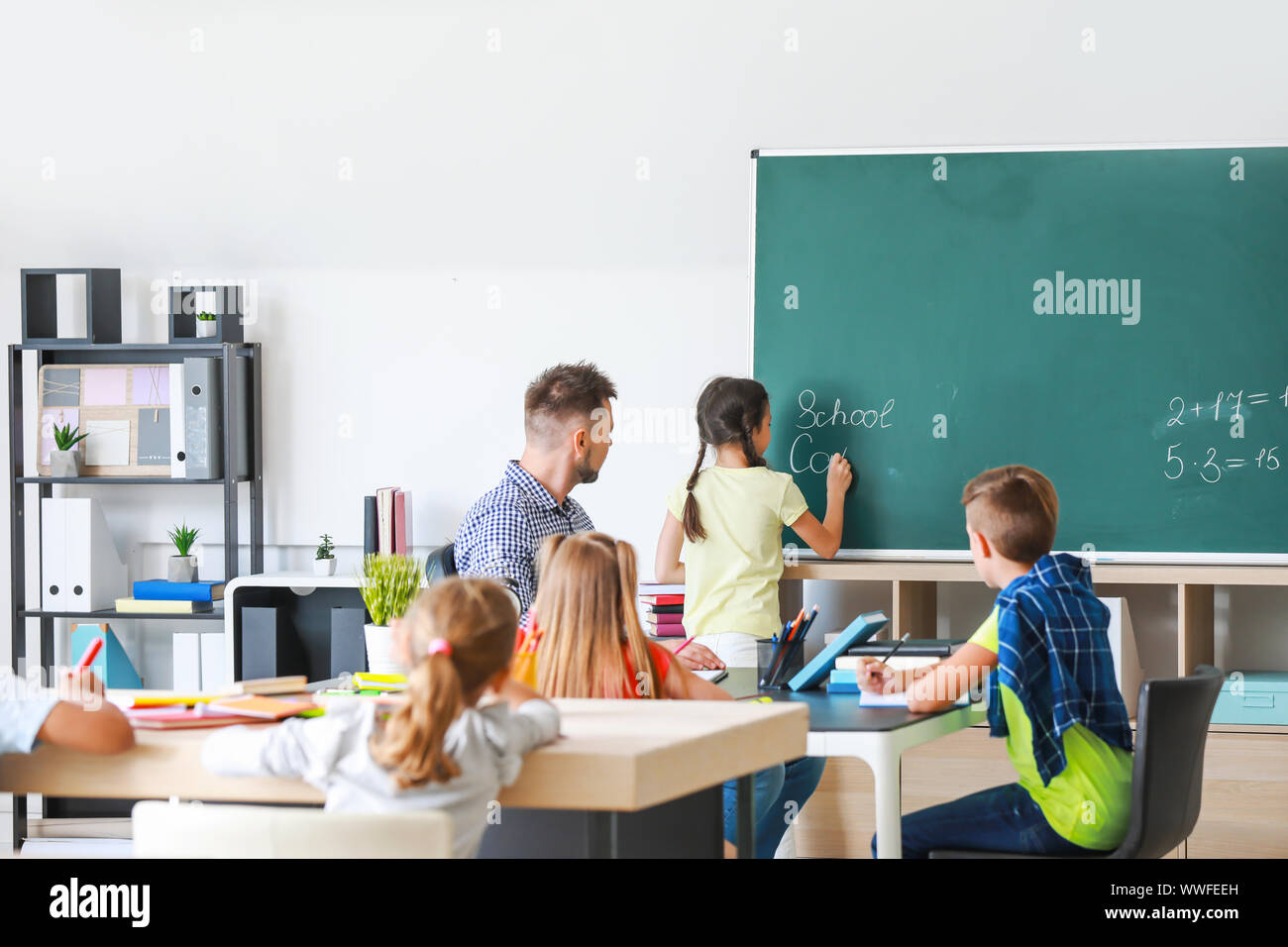 Cute children with teacher during lesson in classroom Stock Photo - Alamy