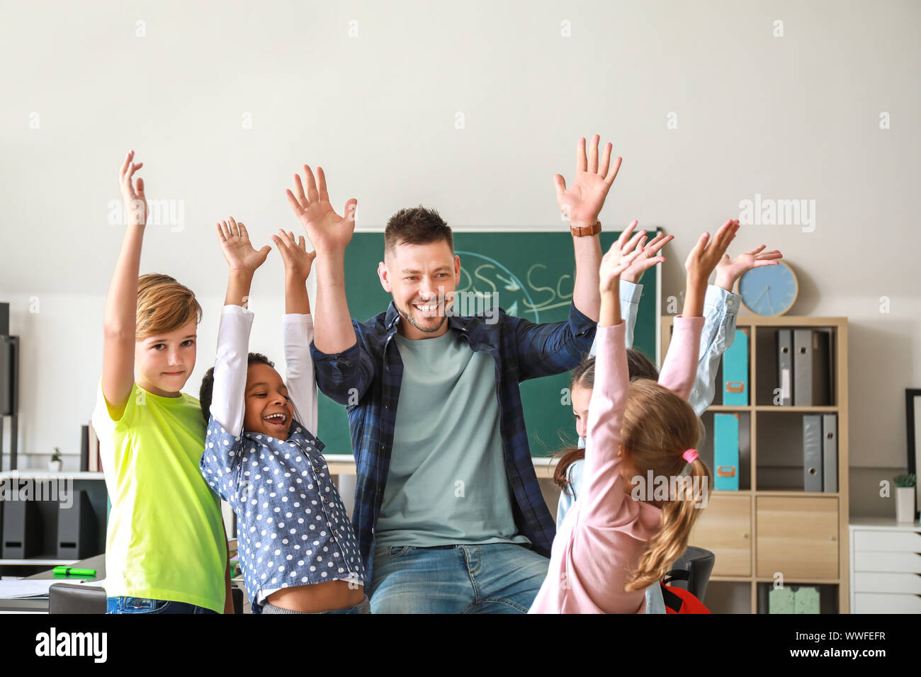 Happy children with teacher in classroom Stock Photo - Alamy