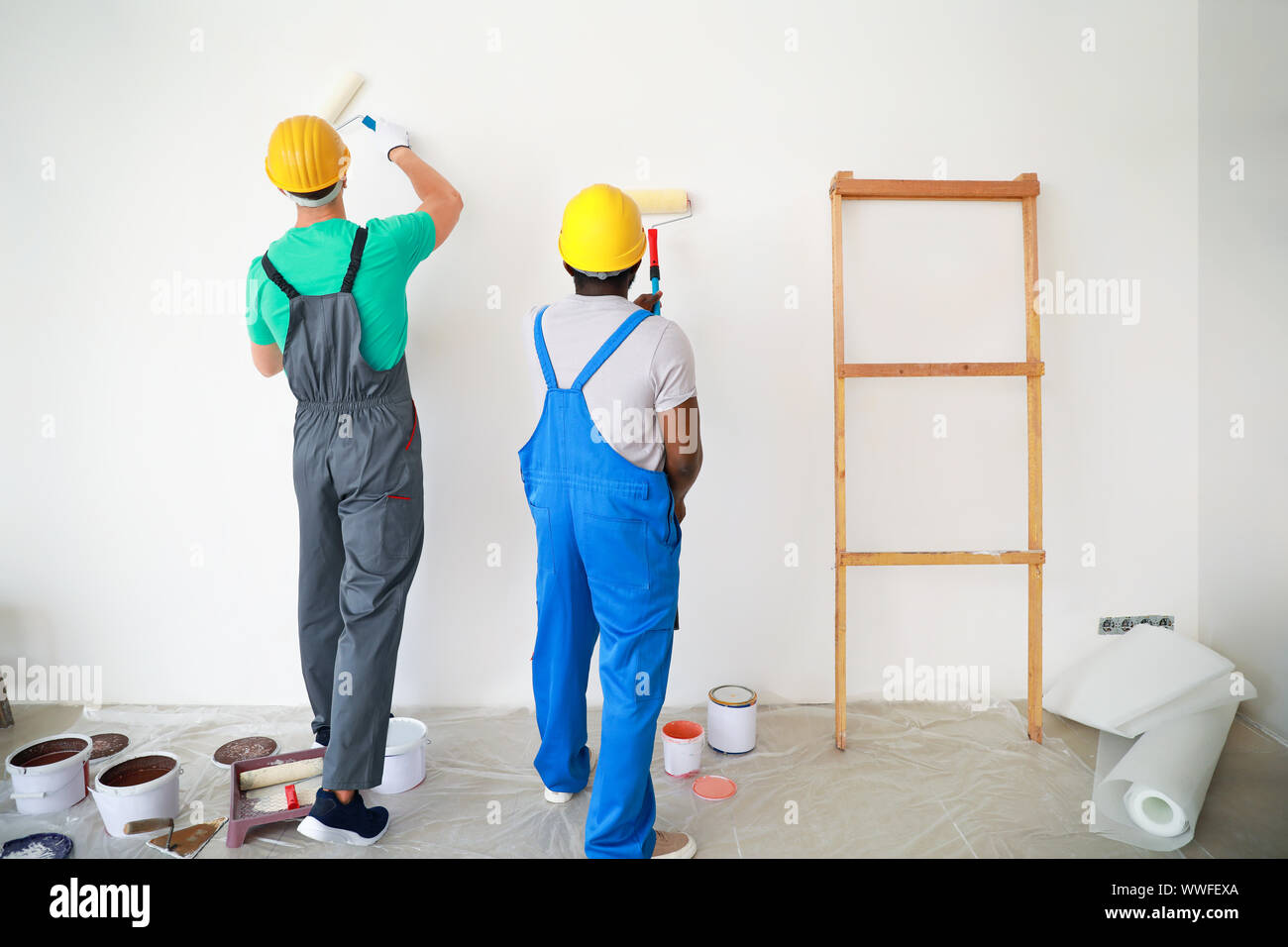 Male decorators painting light wall Stock Photo - Alamy