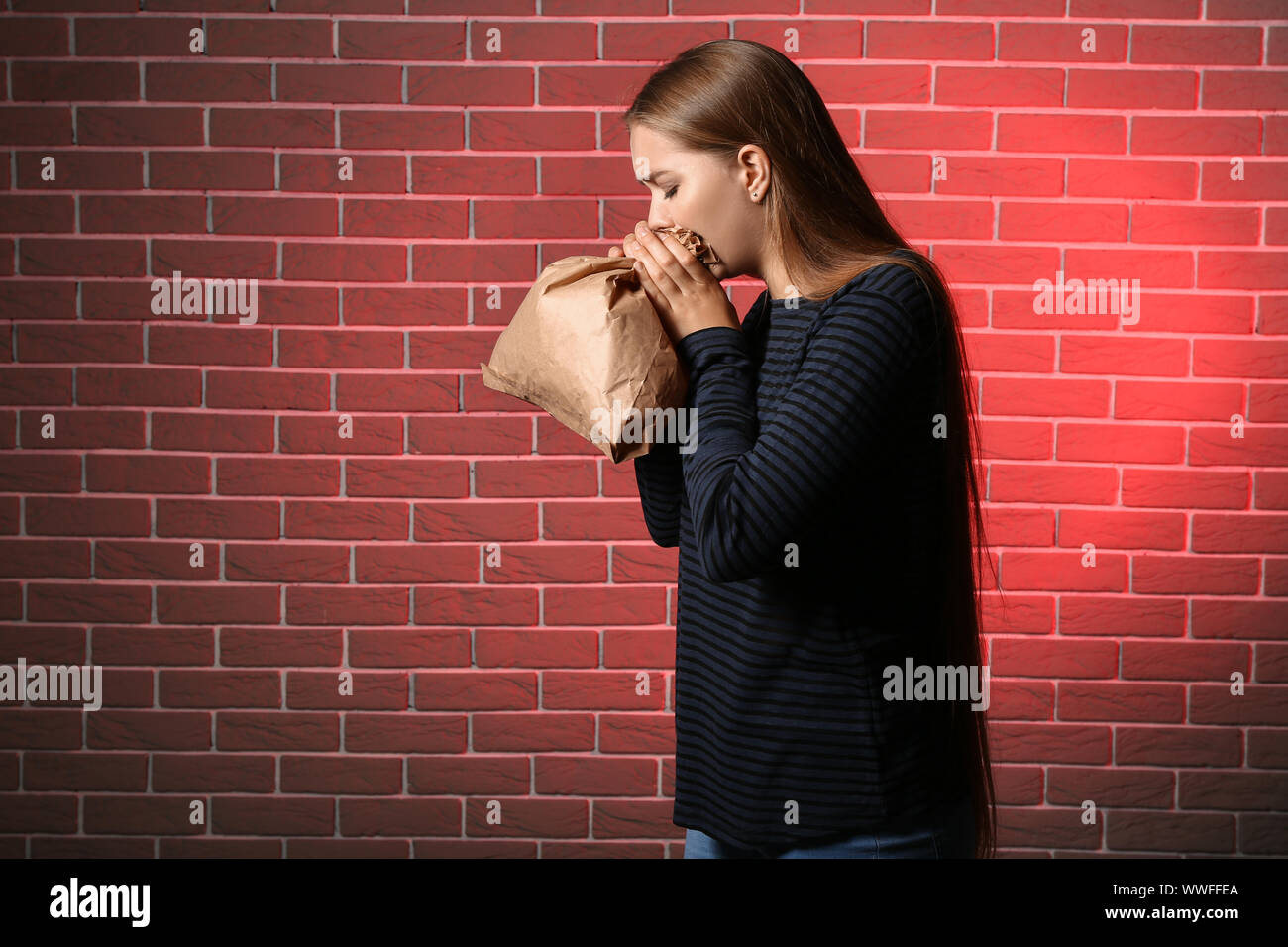 Woman having panic attack against brick wall Stock Photo - Alamy