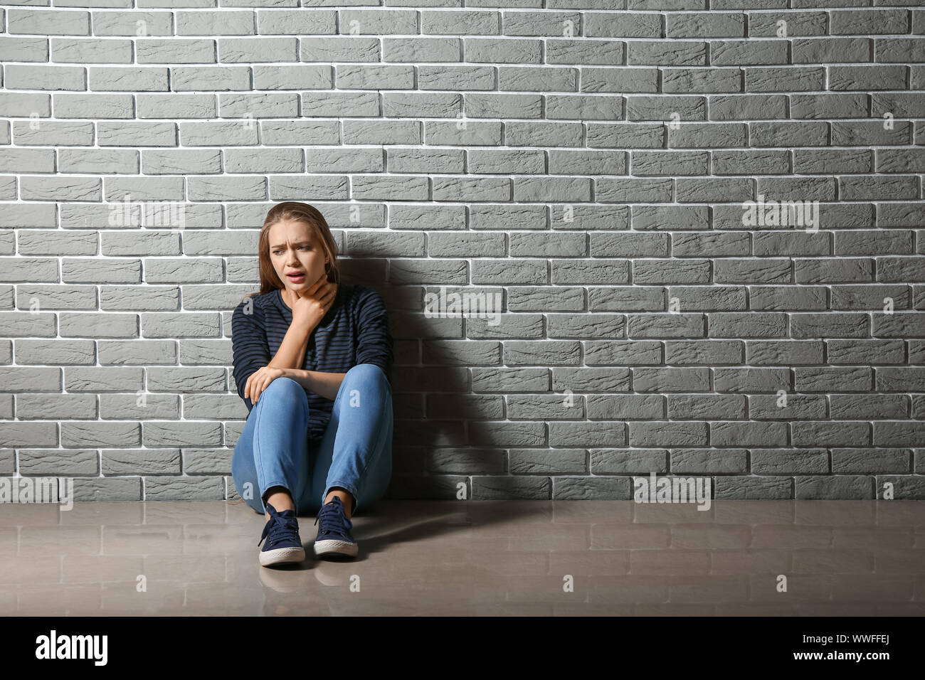 Woman having panic attack while sitting near brick wall Stock Photo - Alamy
