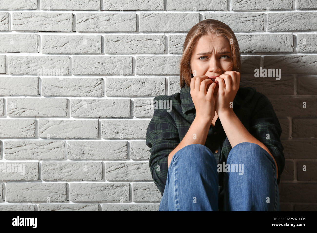 Woman having panic attack while sitting near brick wall Stock Photo - Alamy