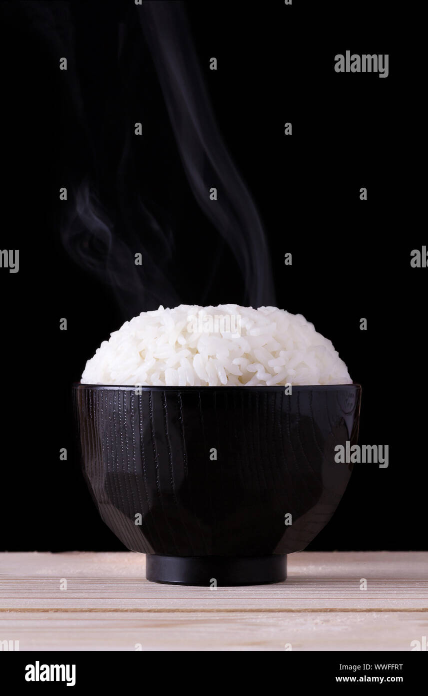 Cooked rice in japanese bowl on black background with smoke, steamed ...