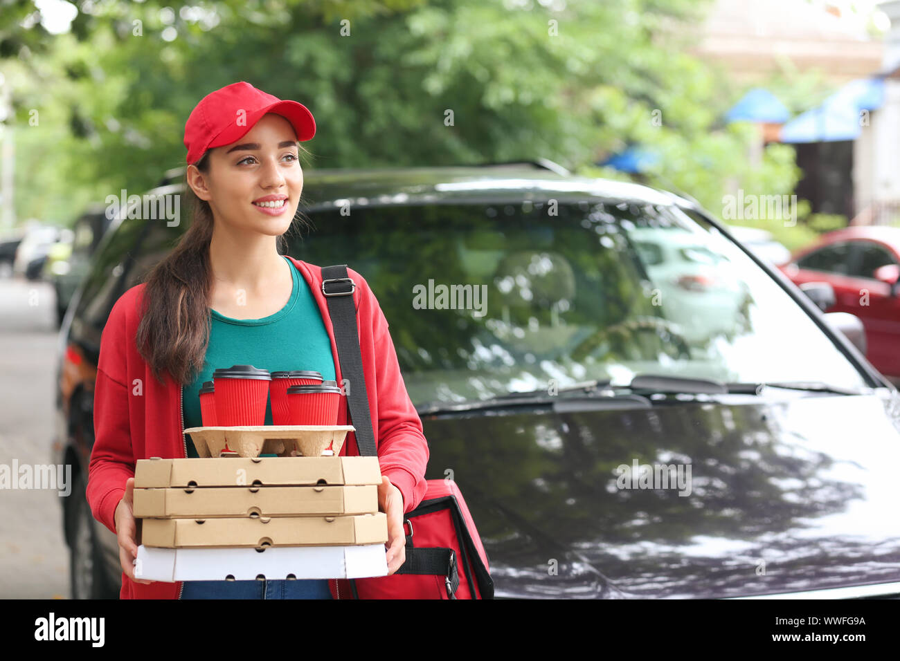 Female worker of food delivery service near car outdoors Stock Photo ...
