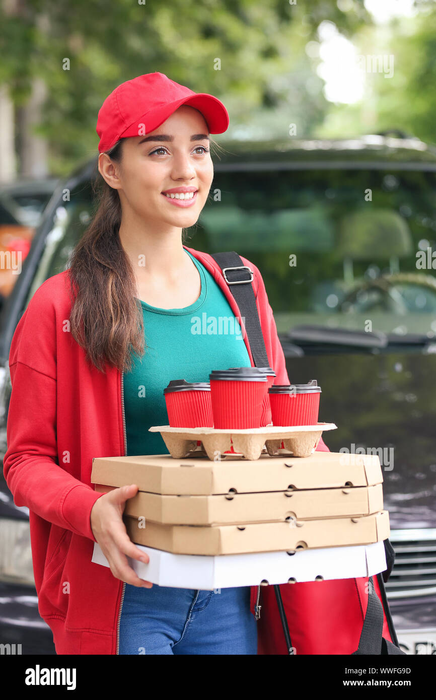 Female worker of food delivery service near car outdoors Stock Photo ...