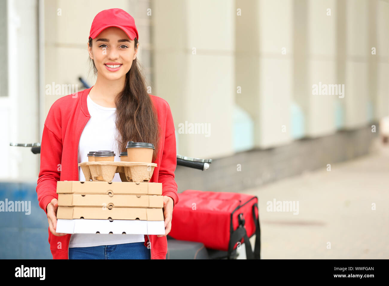 Female worker of food delivery service near scooter outdoors Stock ...