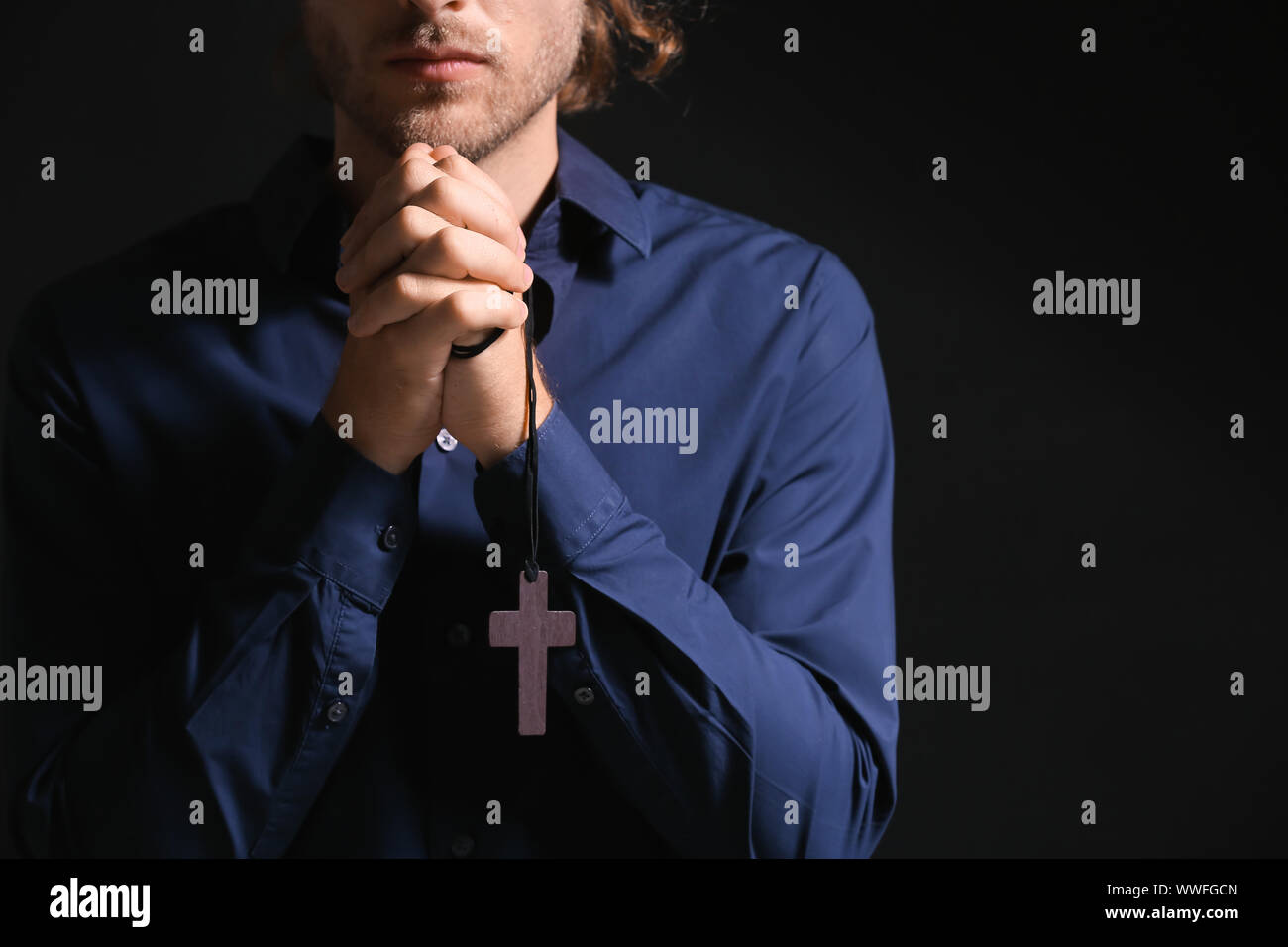 Religious young man praying on dark background Stock Photo - Alamy