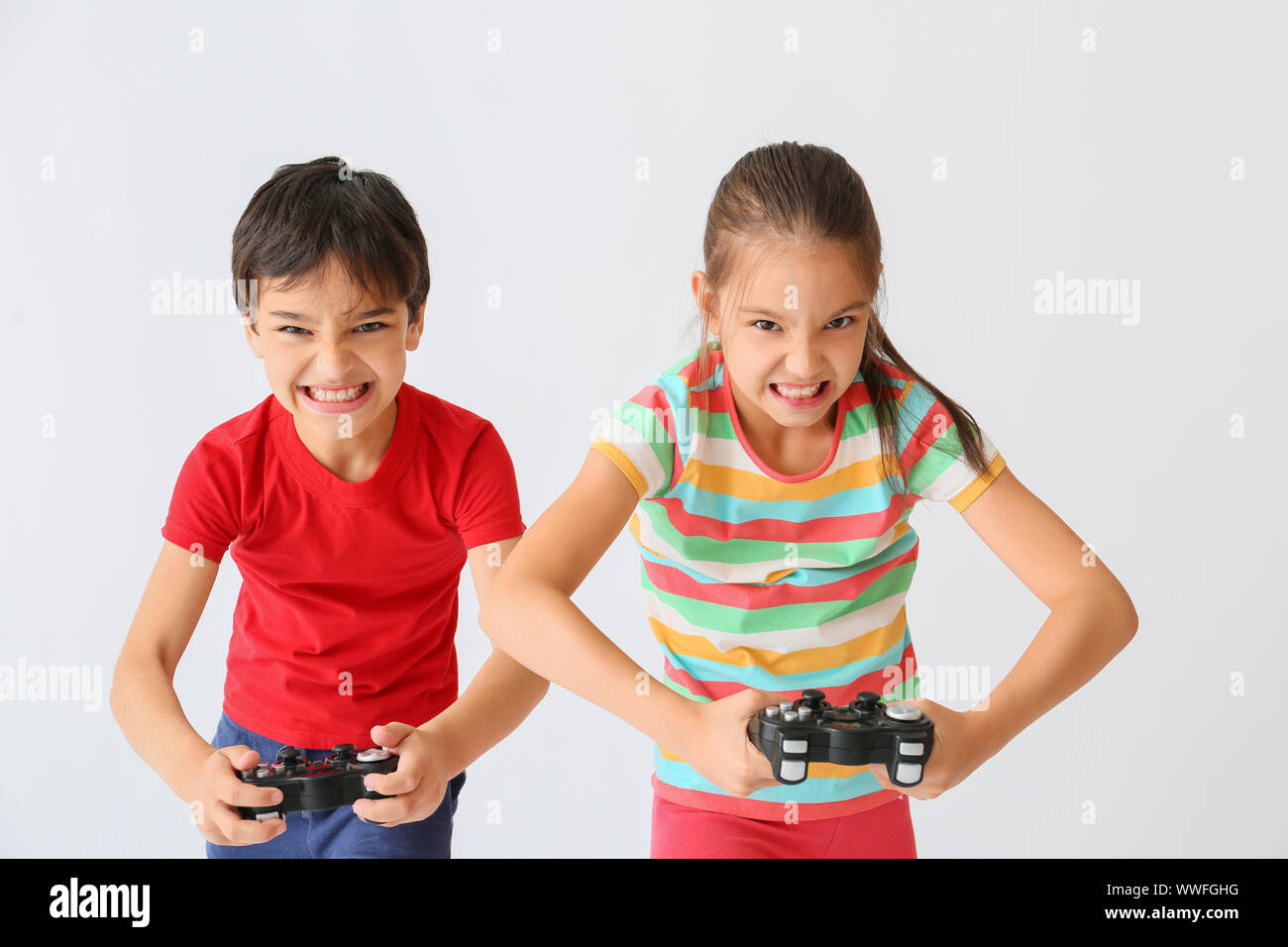 Emotional children playing video games on light background Stock Photo ...
