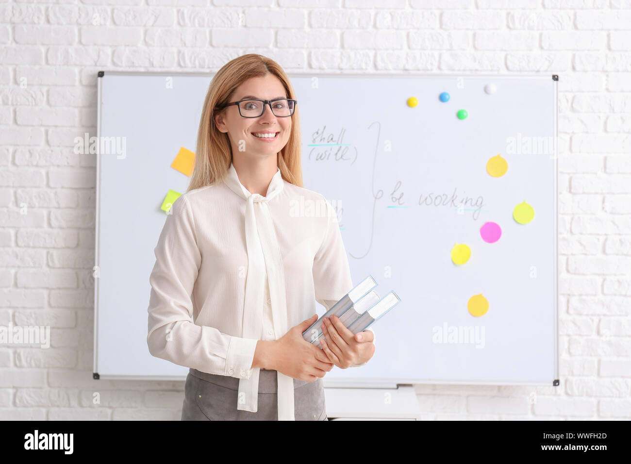 Beautiful English teacher with books in classroom Stock Photo - Alamy