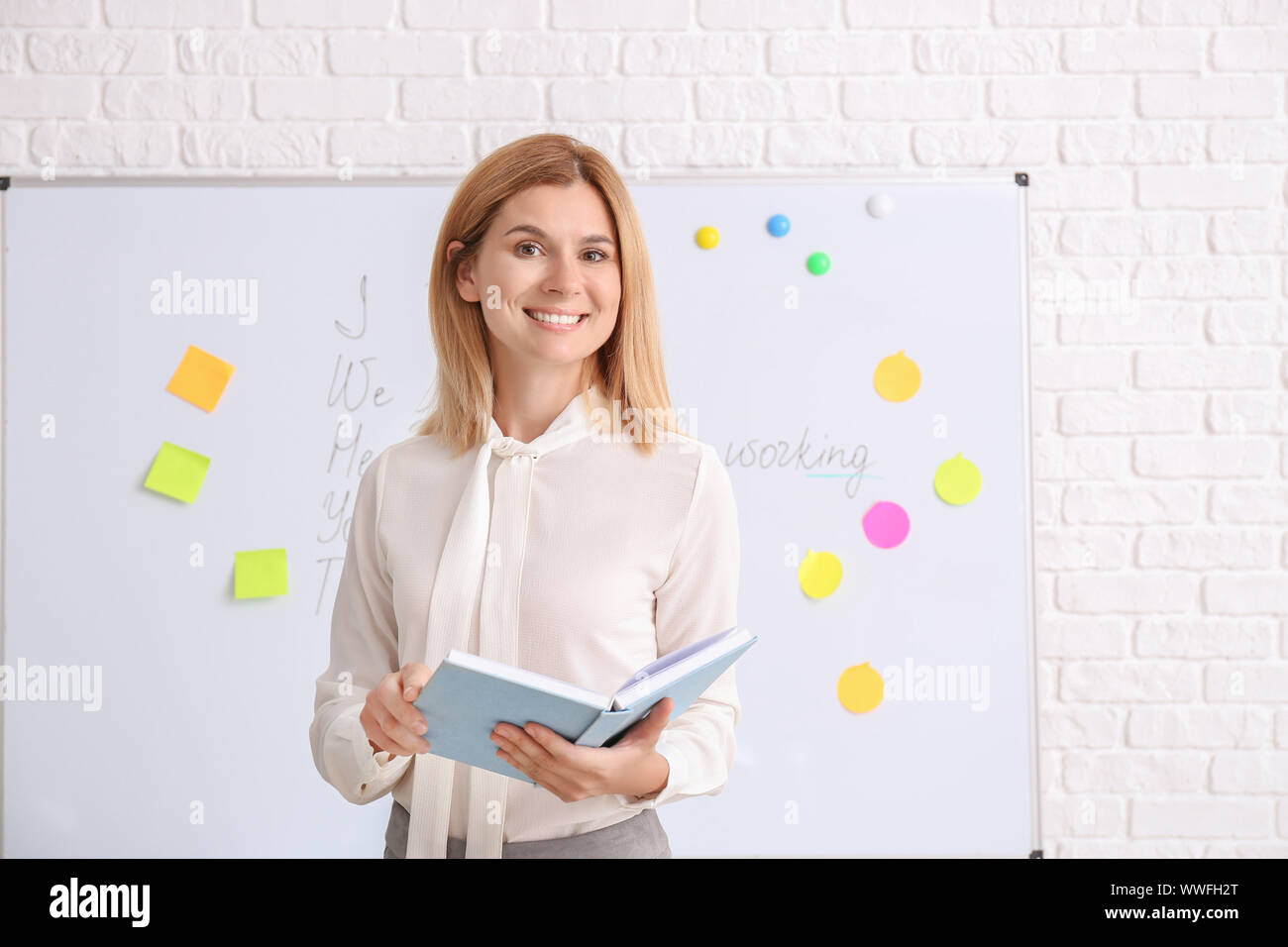 Beautiful English teacher with book in classroom Stock Photo - Alamy