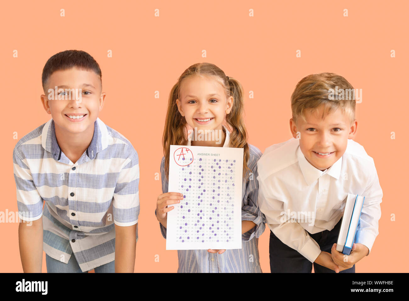 Happy children with answer sheet for school test on color background ...