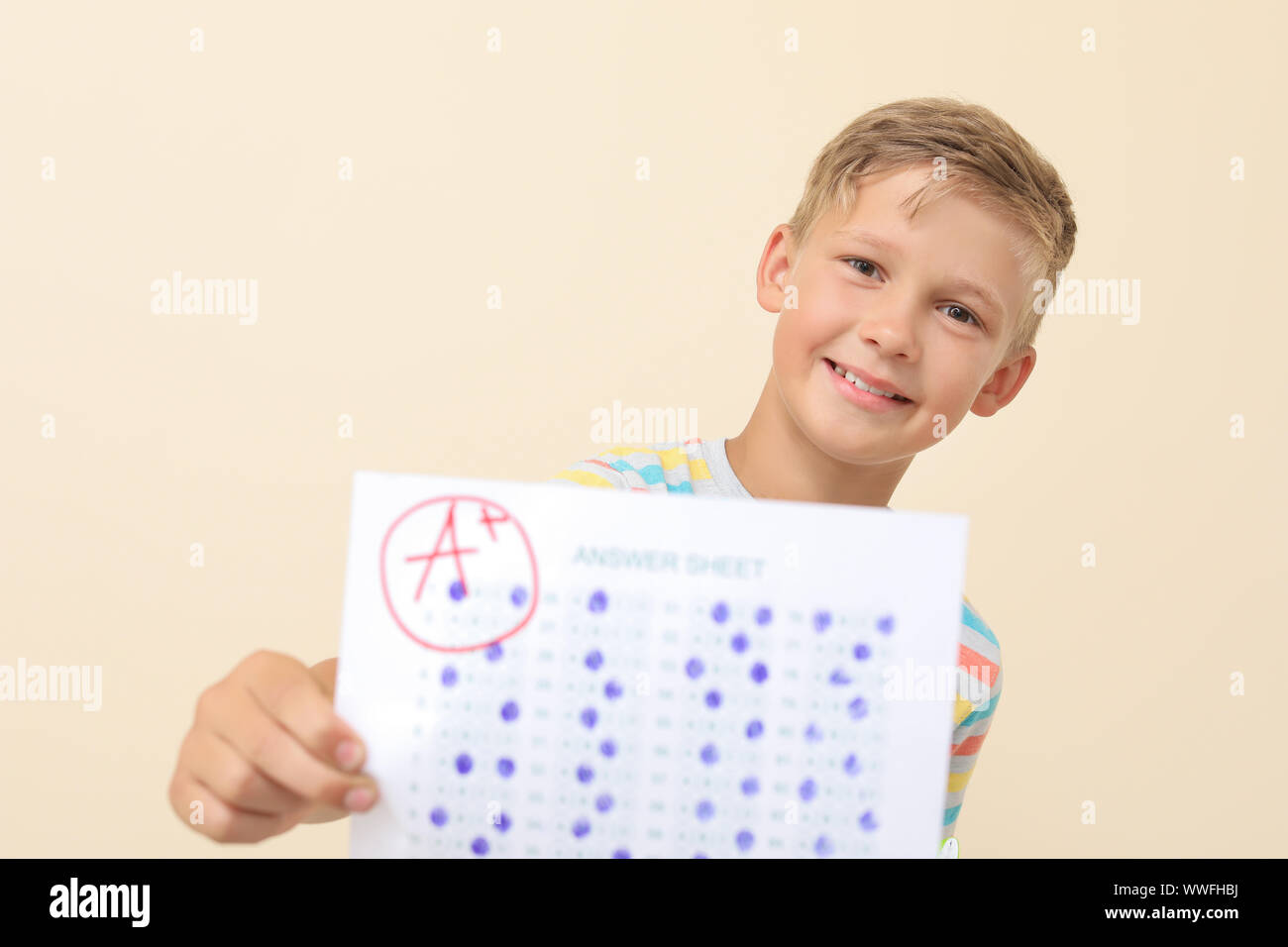 Happy boy with answer sheet for school test on light background Stock ...