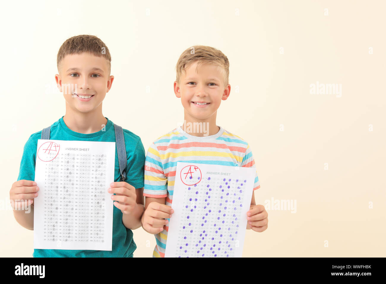 Happy boys with answer sheets for school test on light background Stock ...