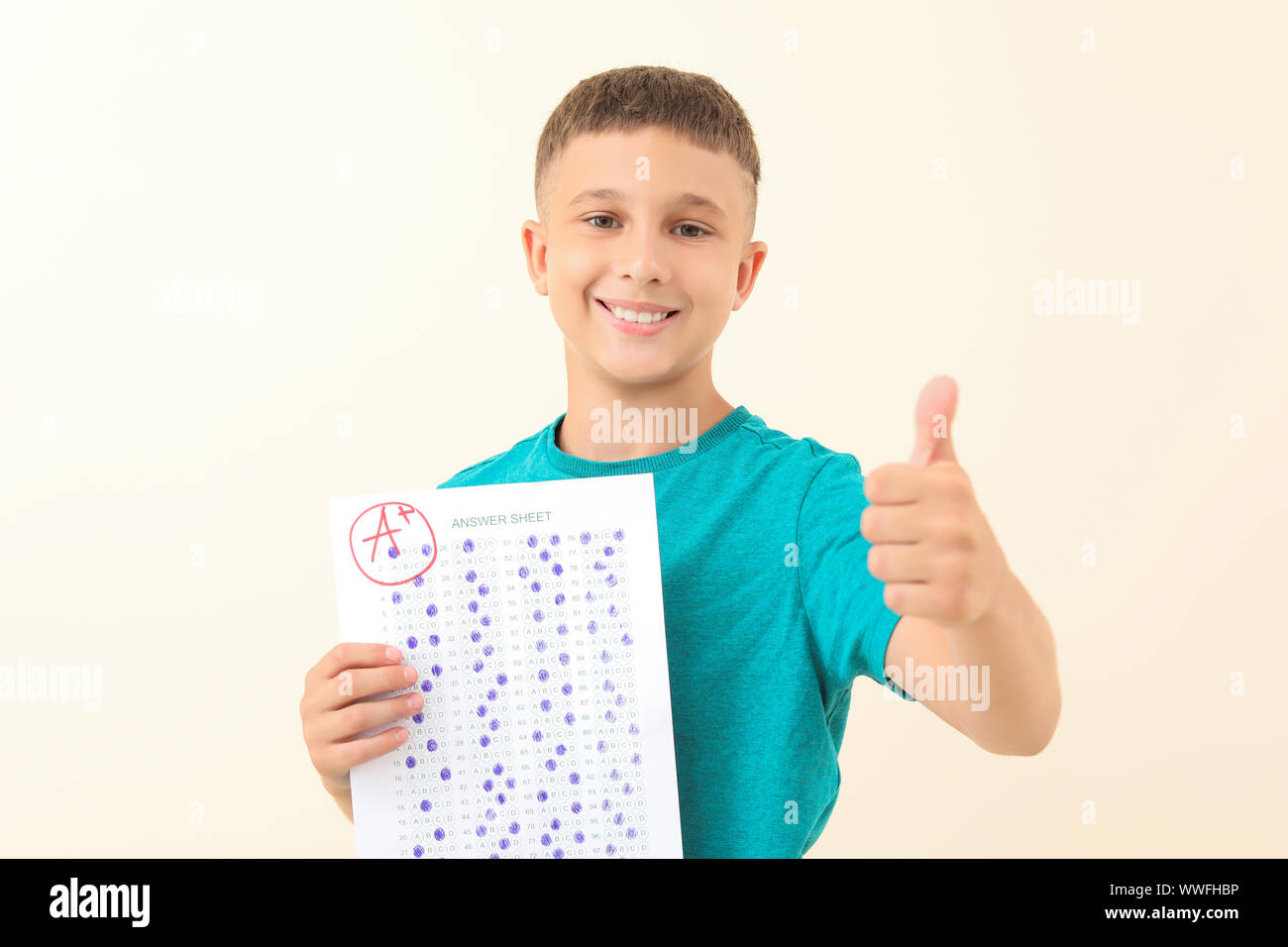 Happy Boy With Answer Sheet For School Test Showing Thumb up On Light happy-boy-with-answer-sheet-for-school-test-showing-thumb-up-on-light