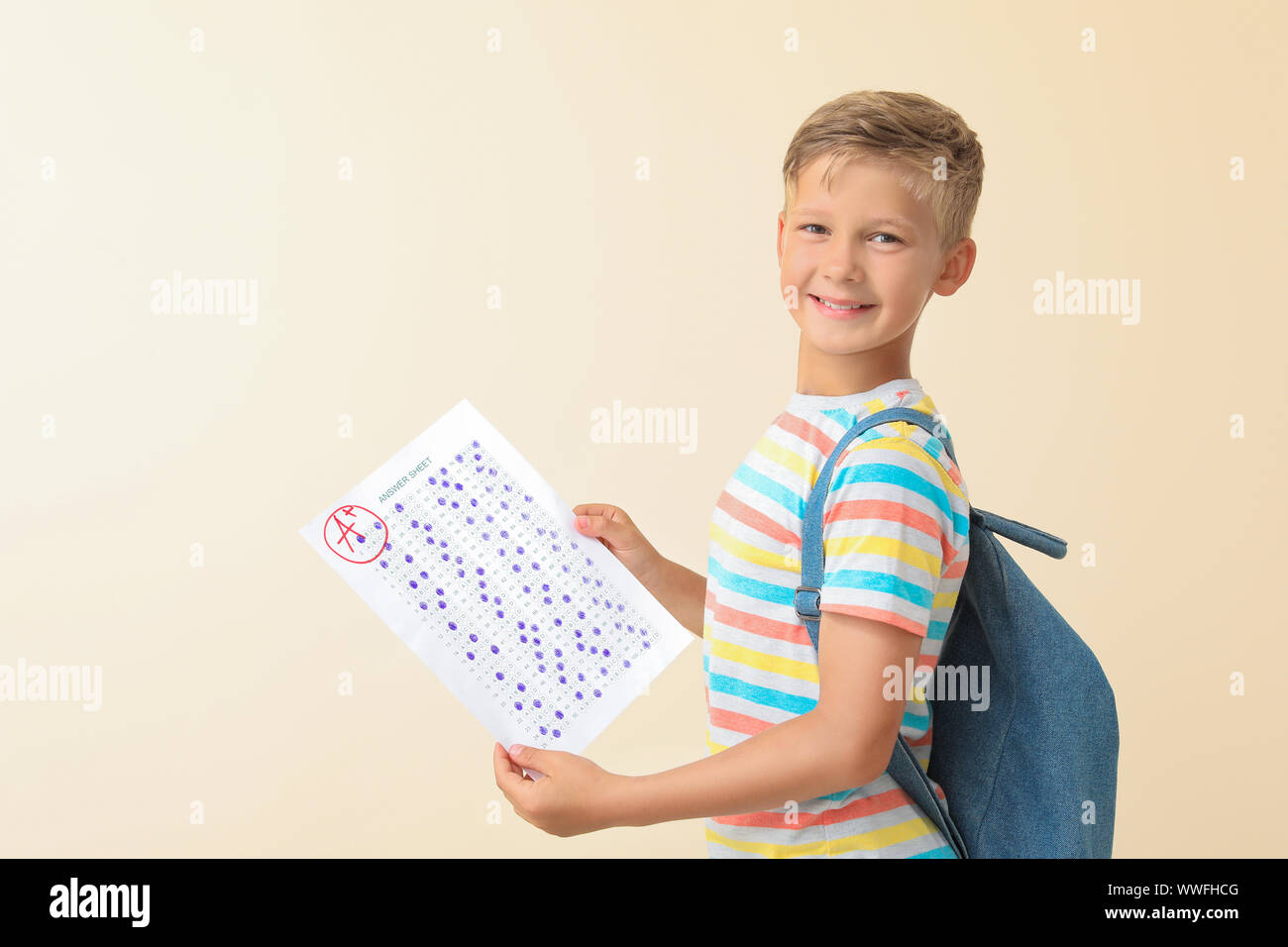 Happy boy with answer sheet for school test on light background Stock ...
