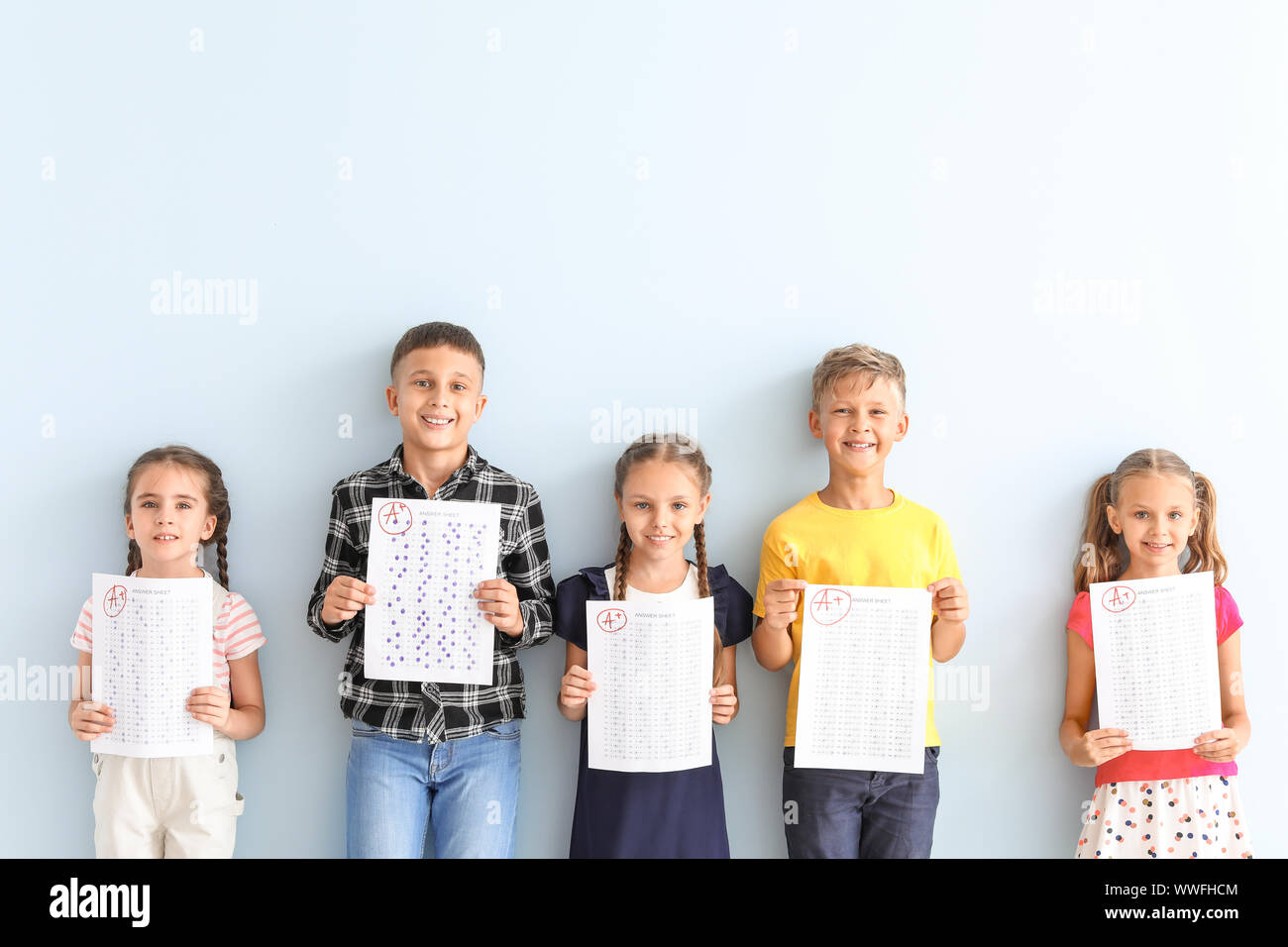 Children with answer sheets for school test on light color background ...