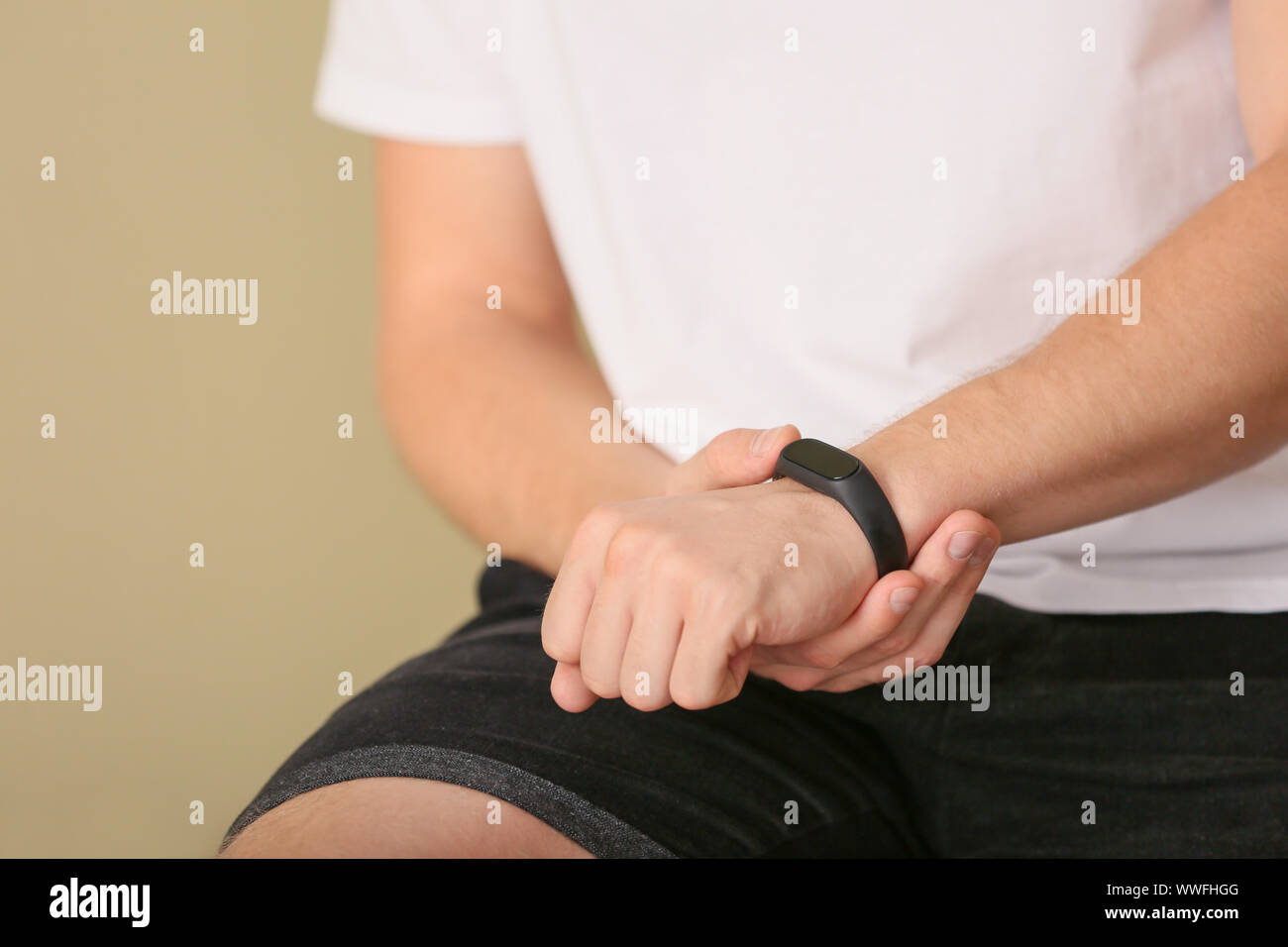 Man with fitness tracker checking his pulse on color background ...