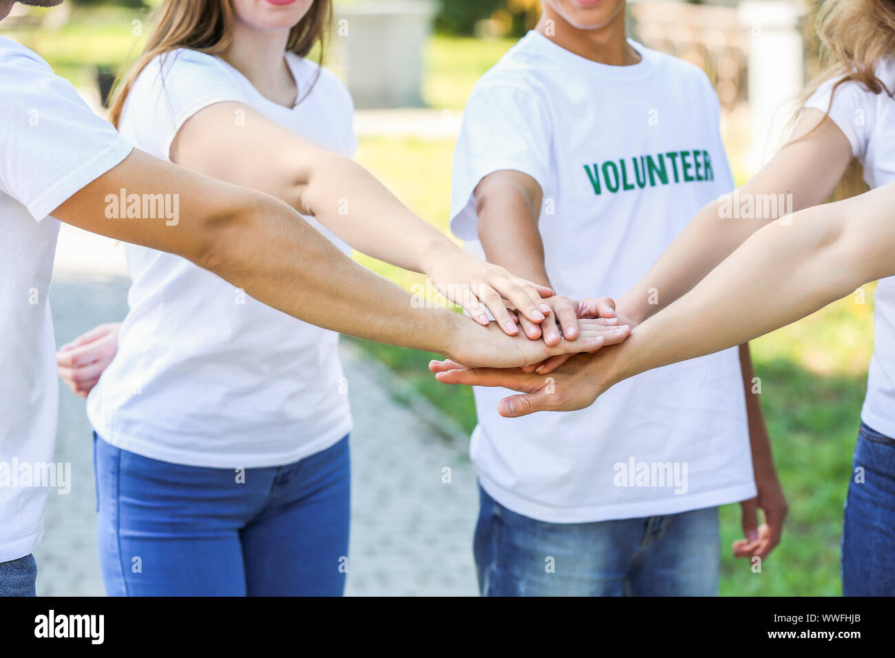 Group of volunteers putting hands together outdoors Stock Photo - Alamy