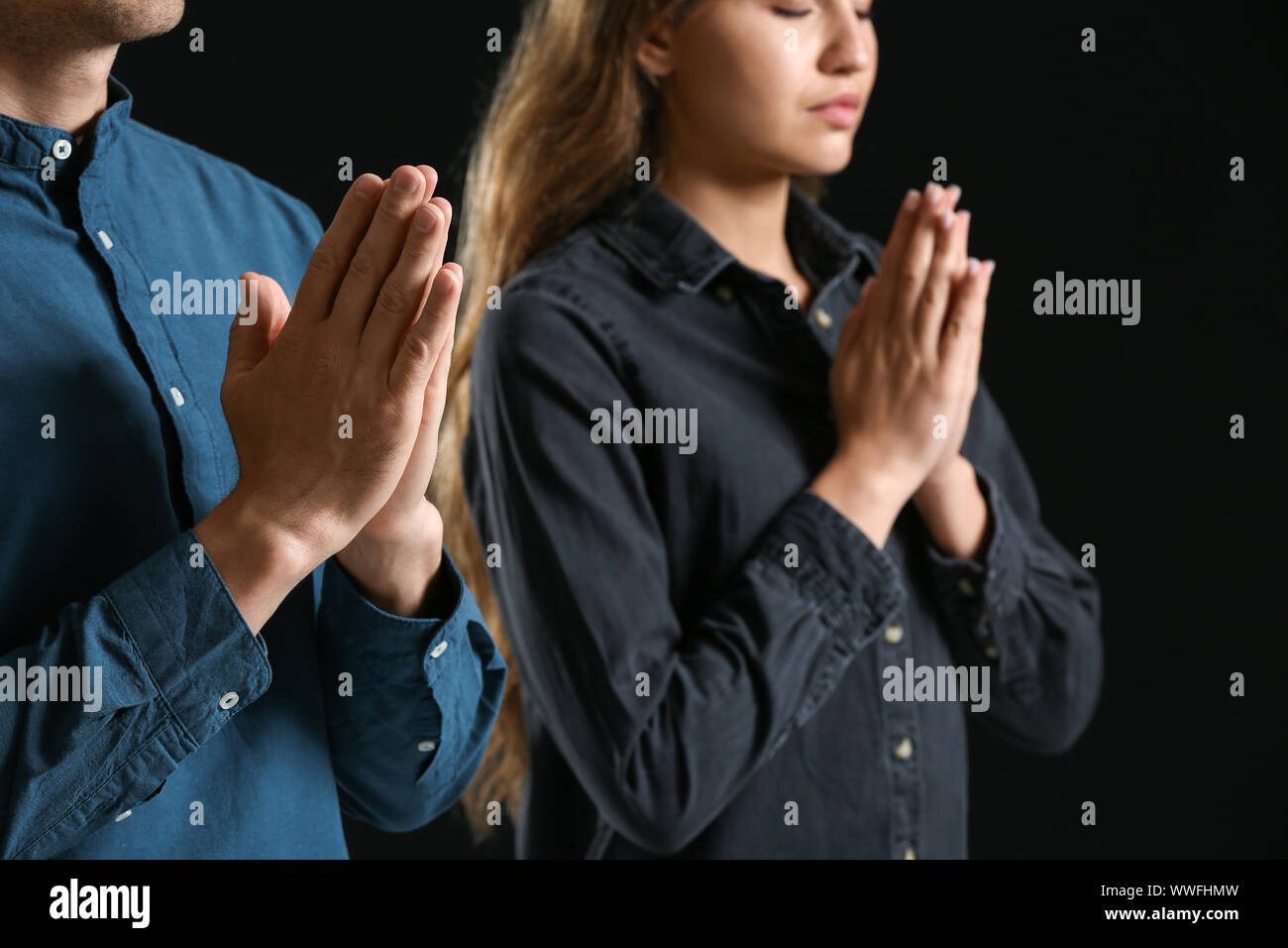 Religious couple praying to God on dark background Stock Photo - Alamy