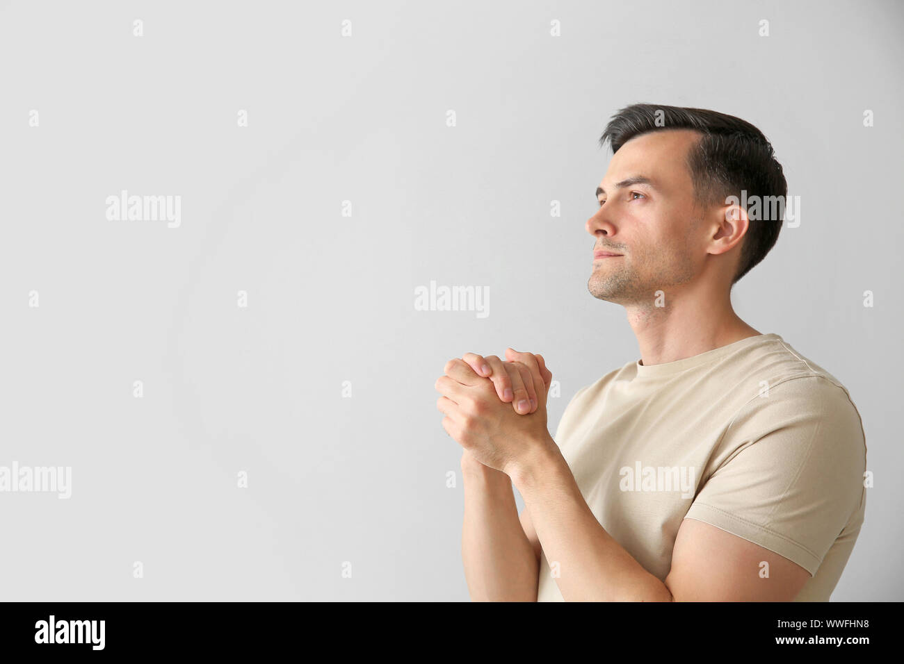 Religious man praying to God on light background Stock Photo - Alamy