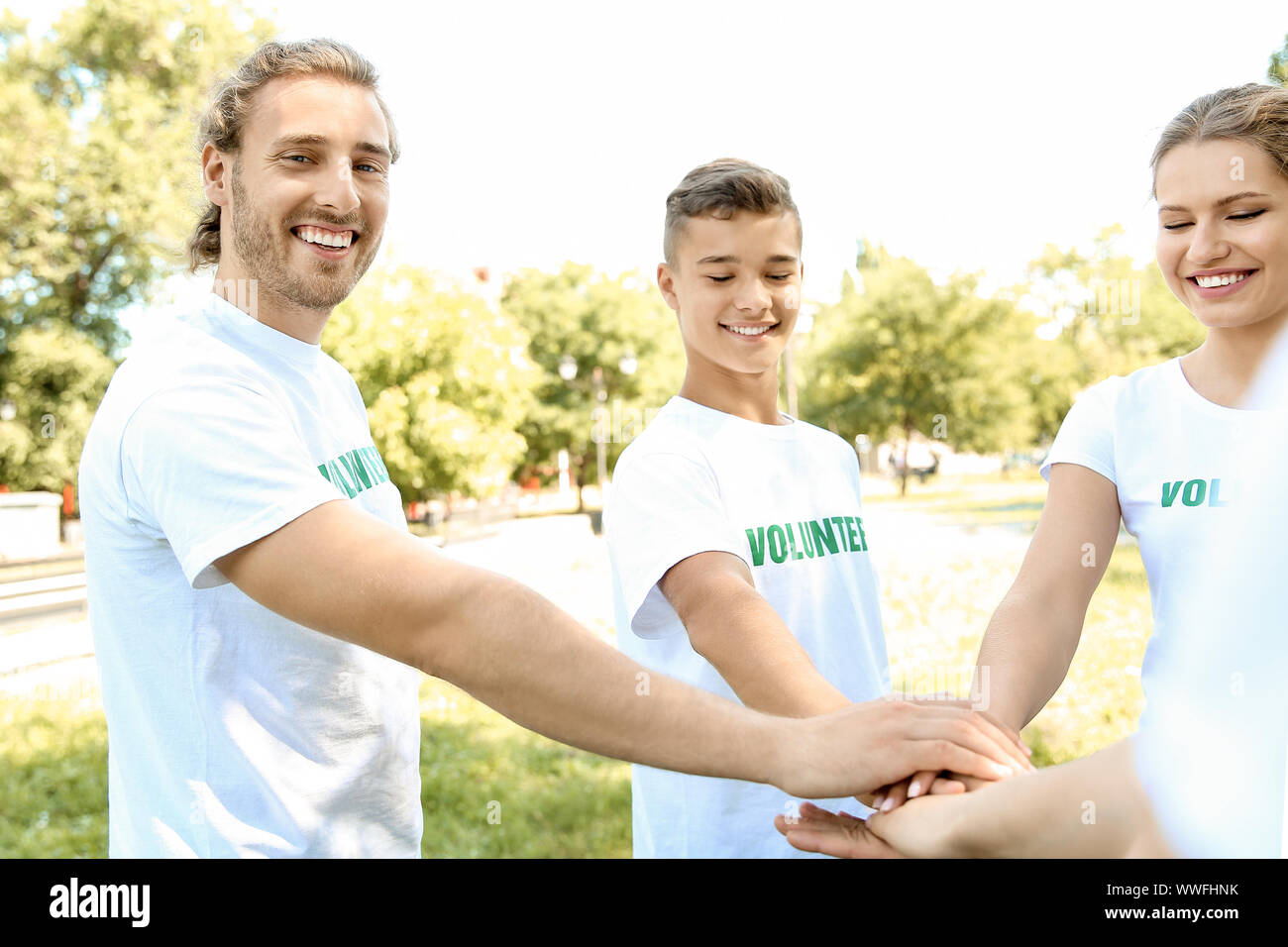 Group of volunteers putting hands together outdoors Stock Photo - Alamy