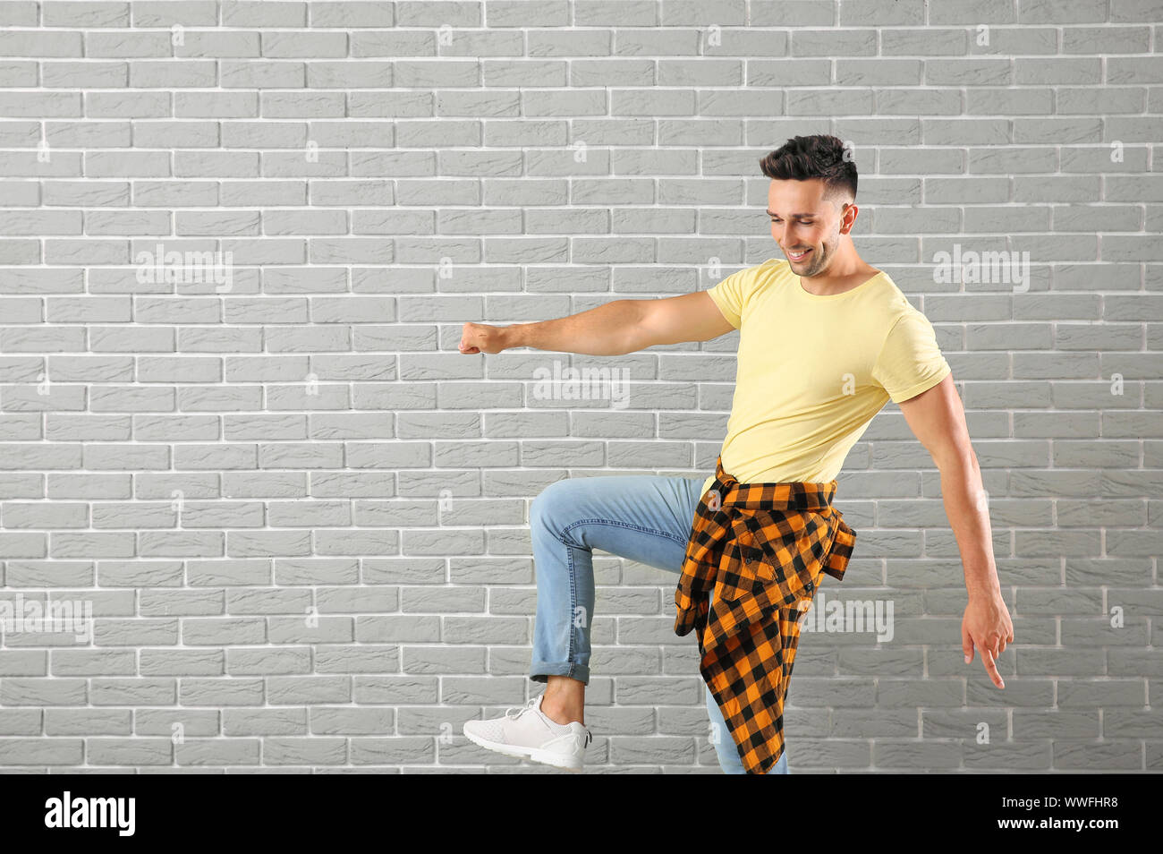 Handsome young man dancing against brick wall Stock Photo - Alamy