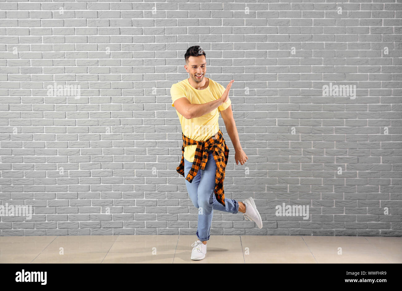 Handsome young man dancing against brick wall Stock Photo - Alamy