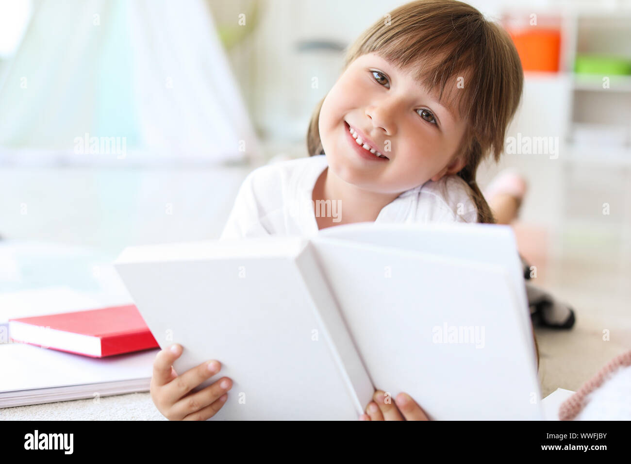 Cute little girl reading book at home Stock Photo - Alamy