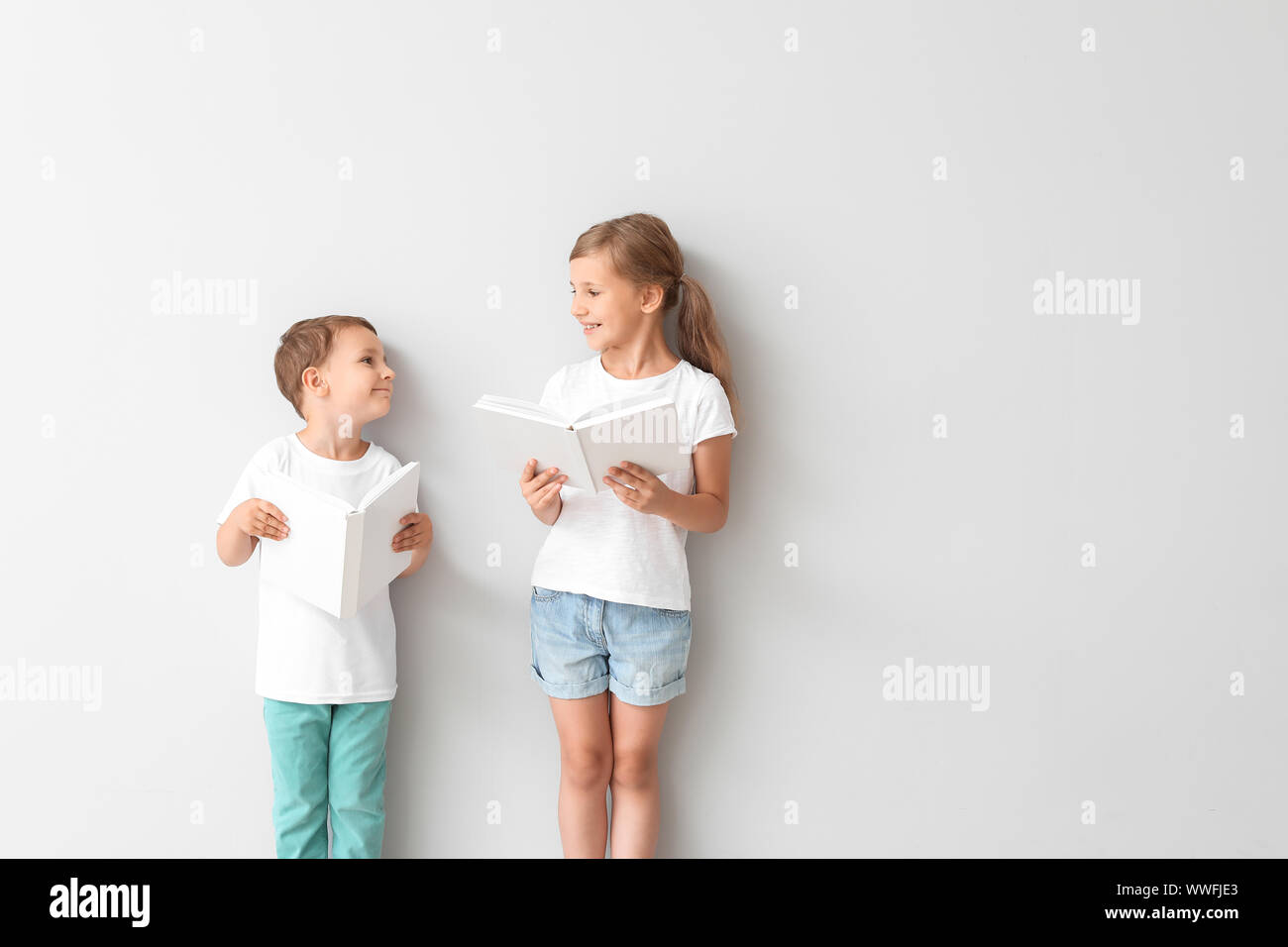 Little children with books on light background Stock Photo - Alamy