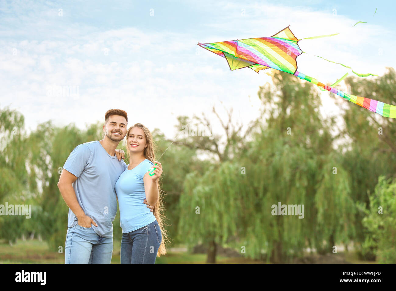 Happy young couple flying kite outdoors Stock Photo - Alamy