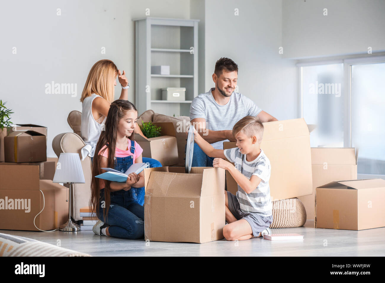 Happy family unpacking belongings in their new house Stock Photo - Alamy