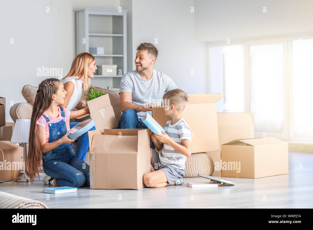 Happy family unpacking belongings in their new house Stock Photo - Alamy