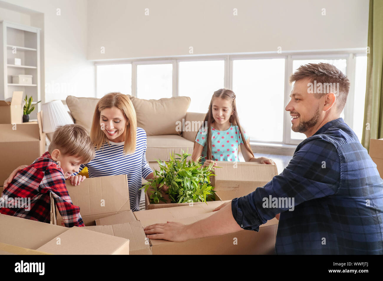 Happy family unpacking belongings in their new house Stock Photo - Alamy