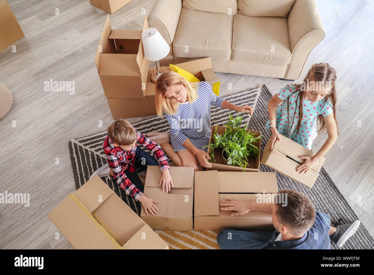 Happy family unpacking belongings in their new house Stock Photo - Alamy