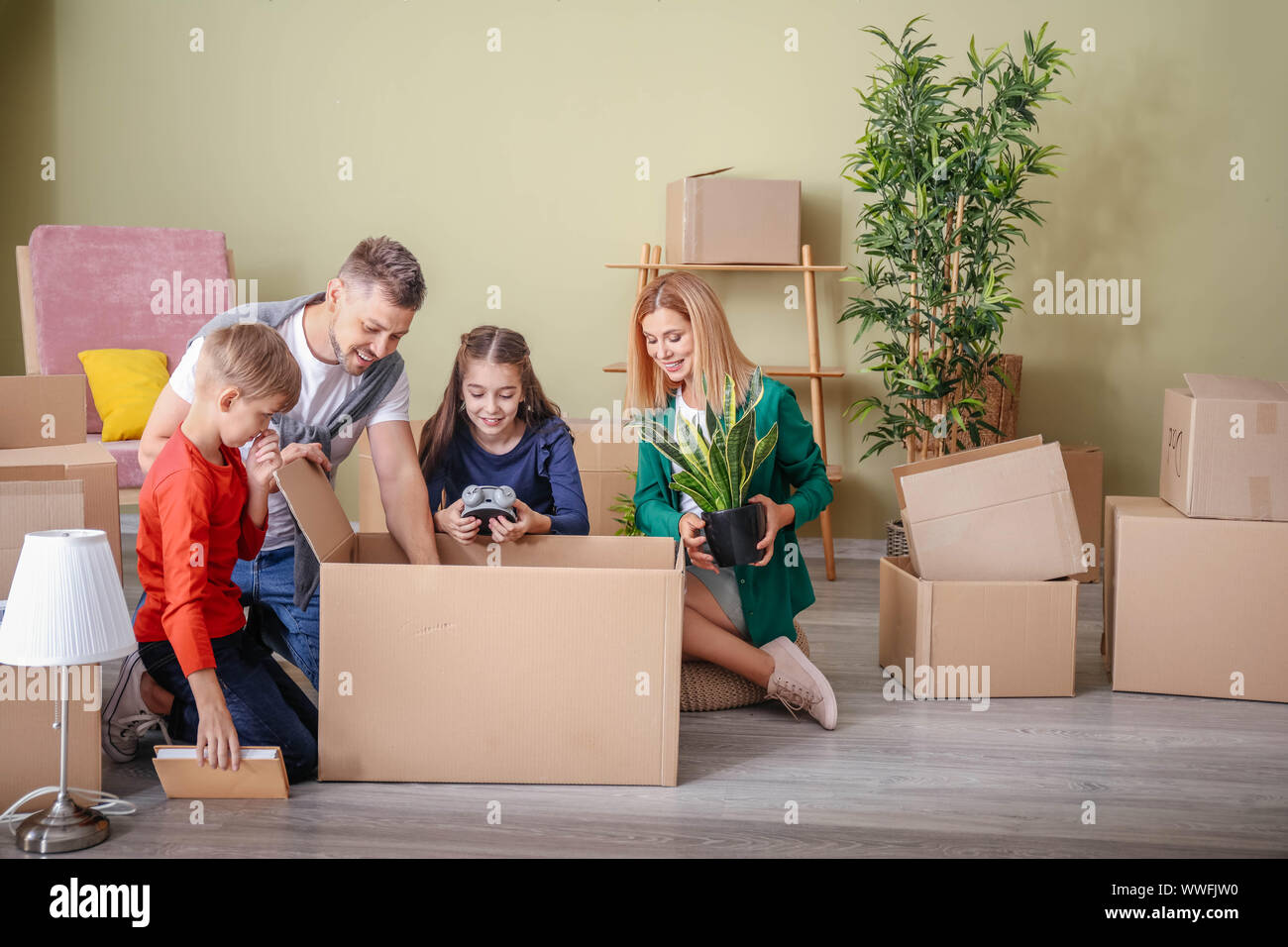 Happy family unpacking belongings in their new house Stock Photo - Alamy