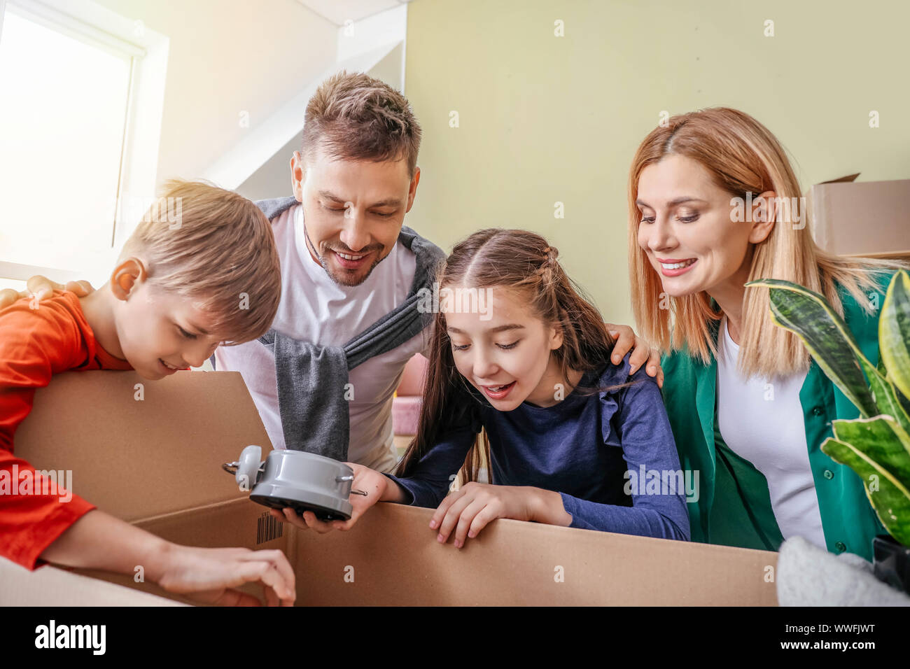 Happy family unpacking belongings in their new house Stock Photo - Alamy