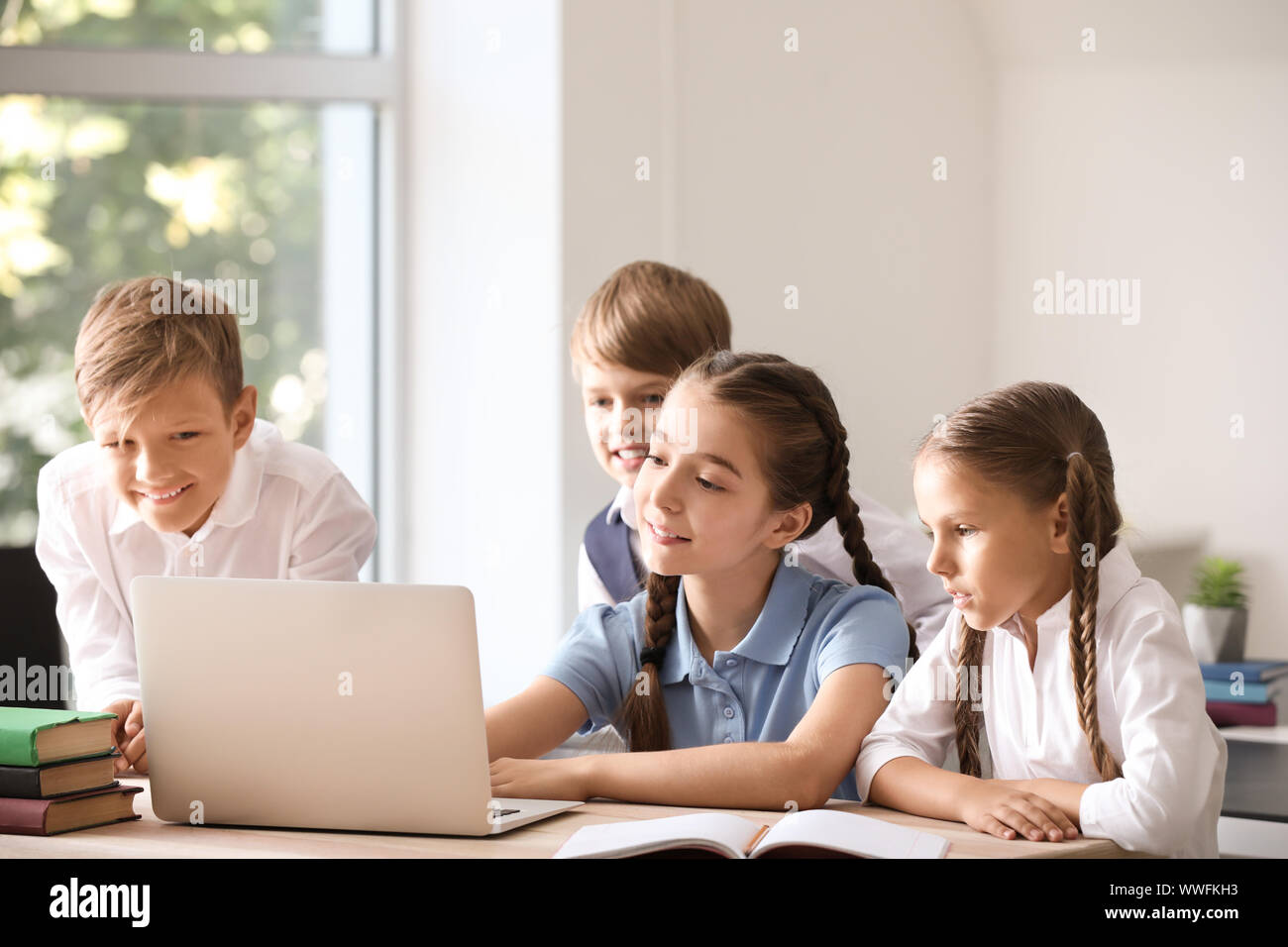 Cute little pupils with laptop in classroom Stock Photo - Alamy